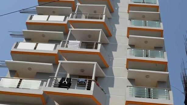 Um hotel de vários andares com varandas, uma placa com a inscrição 'Hotel Sea Shine' e vista do céu.
