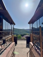Escadaria que leva a um terraço com grades de vidro e vista para uma paisagem montanhosa.