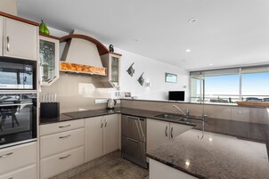 Cozinha moderna com forno embutido, lava-louças e uma ilha grande com pia.