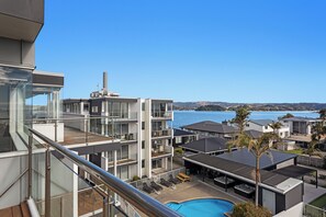 Um edifício moderno com piscina, área de estar ao ar livre e vista para a água.