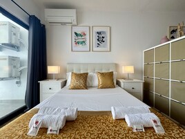 Quarto de hotel com cama, duas mesinhas de cabeceira, um guarda-roupa e duas obras de arte emolduradas na parede.