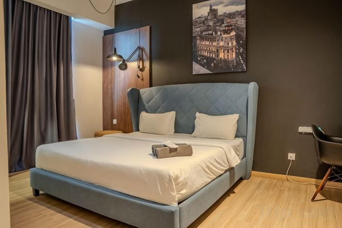 Quarto de hotel moderno com uma cama grande, uma escrivaninha e uma cadeira.