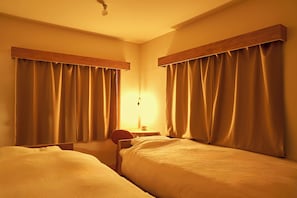 Quarto de hotel com duas camas, uma escrivaninha e uma cadeira.