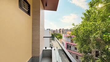 Um edifício residencial com varanda, vista para a rua e edifícios vizinhos.
