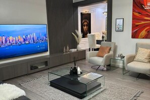 Uma sala de estar moderna com televisão de tela plana, mesa de centro de vidro e móveis contemporâneos.