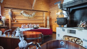 Interior de cabana de madeira com cama, banheira de madeira, lareira e decoração rústica.
