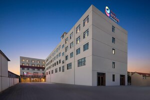 Um hotel moderno com fachada plana, várias janelas e um logotipo marcante no topo.