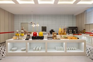 Disposição de buffet com diversos alimentos, utensílios, um espelho e uma parede revestida de azulejos.