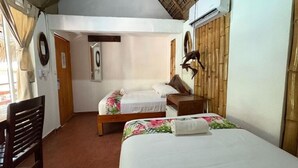 Quarto com duas camas, uma cadeira de madeira, uma mesinha e uma luminária na parede.
