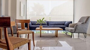 Uma sala de estar moderna com um sofá, duas poltronas, uma mesa de centro e um vaso de planta.