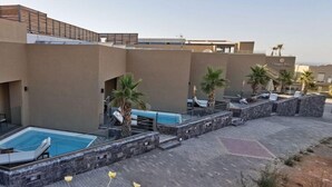 Uma área de piscina no terraço com espreguiçadeiras, palmeiras e uma vista desobstruída do horizonte da cidade.