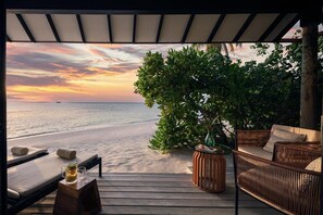 Um espaço de relaxamento à beira-mar, com vista para o oceano e um pôr do sol.