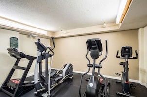 Sala de ginástica com três bicicletas ergométricas, esteira e remo.