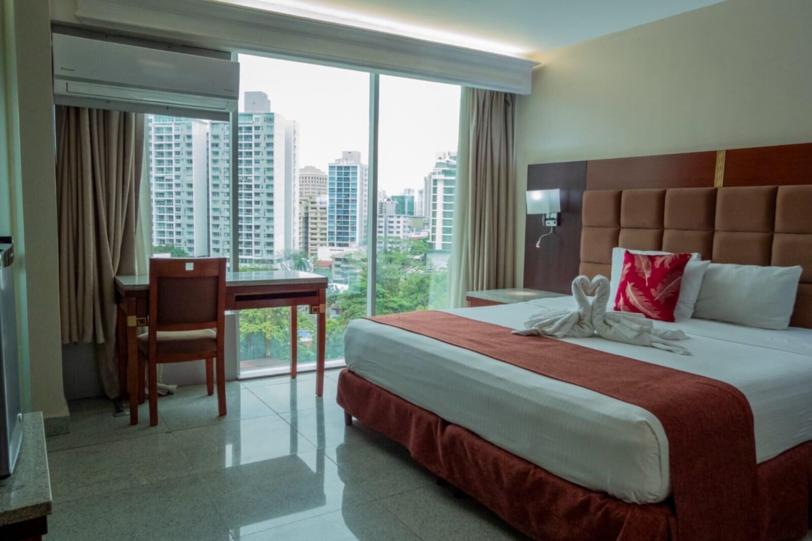 Quarto de hotel com uma cama, uma escrivaninha e uma cadeira.