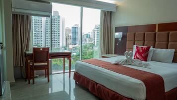Quarto de hotel com uma cama, uma escrivaninha e uma cadeira.