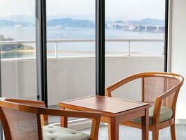Quarto com vista para uma ponte e para a água, uma mesa de madeira e duas cadeiras.