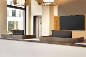Uma mesa de recepção com uma televisão de tela plana, um laptop e uma cadeira.