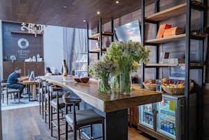 Uma área de bar moderna com um balcão comprido, vários bancos e uma geladeira repleta de bebidas.