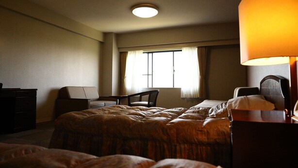 Quarto de hotel com cama, secretária, cadeira e luminária.