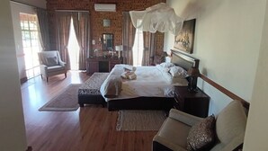 Quarto com uma cama grande, uma escrivaninha, uma cadeira e uma janela.