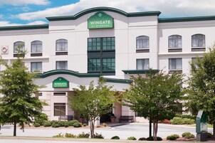 Um hotel chamado Wingate by Wyndham com fachada simétrica, várias janelas e telhado verde.