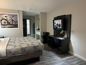 Quarto com cama, escrivaninha, televisão e pintura de bicicleta.