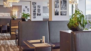 Um hall de hotel moderno com área de estar, exposições de fotos nas paredes e um candelabro.