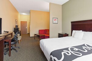 Quarto de hotel com cama, escrivaninha, cadeira e um sofá vermelho.