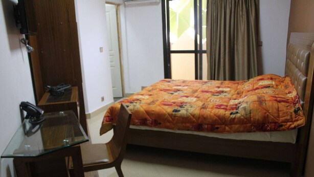 Um quarto com uma cama, uma escrivaninha e uma cadeira.