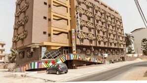 Um edifício com vários andares e fachada singular, com padrões geométricos e uma entrada destacada com degraus coloridos.