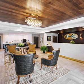 Um saguão de hotel com balcão de recepção, área de estar e um candelabro.