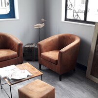 Quarto com duas poltronas de couro, uma pequena mesa de madeira e uma luminária de chão.