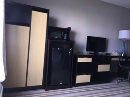 Quarto de hotel com escrivaninha, televisão, micro-ondas, telefone e abajur.