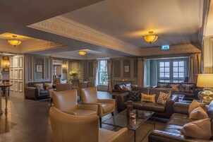 A spacious lobby with leather sofas, a coffee table, and a chandelier.