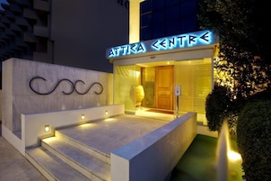 Entrada de um edifício com uma placa indicando 'ATTIKA CENTRE' e uma escadaria que leva à porta.