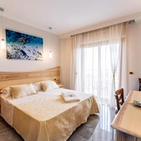 Quarto de hotel com cama, mesa de jantar e um quadro na parede.