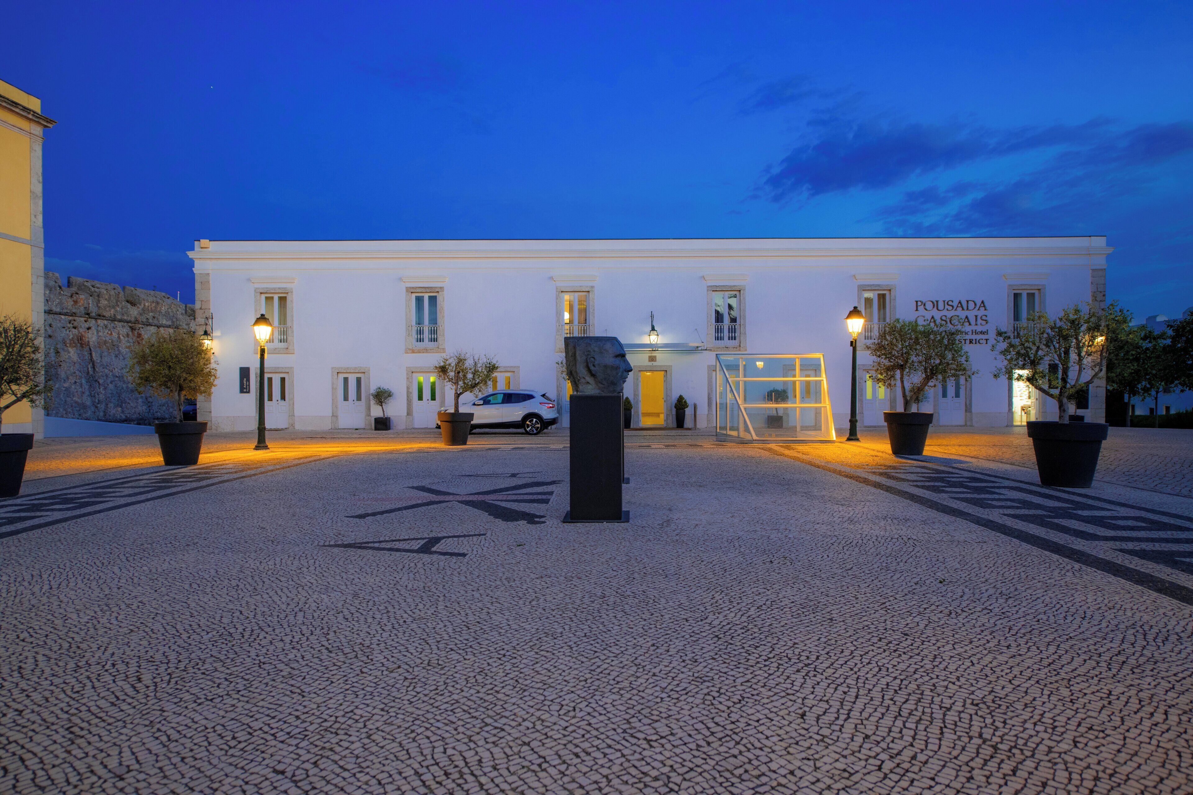 Um edifício branco com uma placa que diz 'Pousada Cascais Hotel District'.