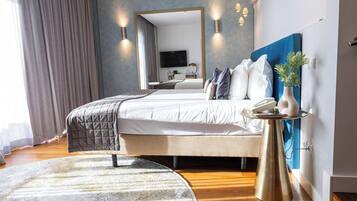 Quarto de hotel moderno com uma cama grande, mesa de cabeceira com telefone, espelho e uma parede azul de destaque.