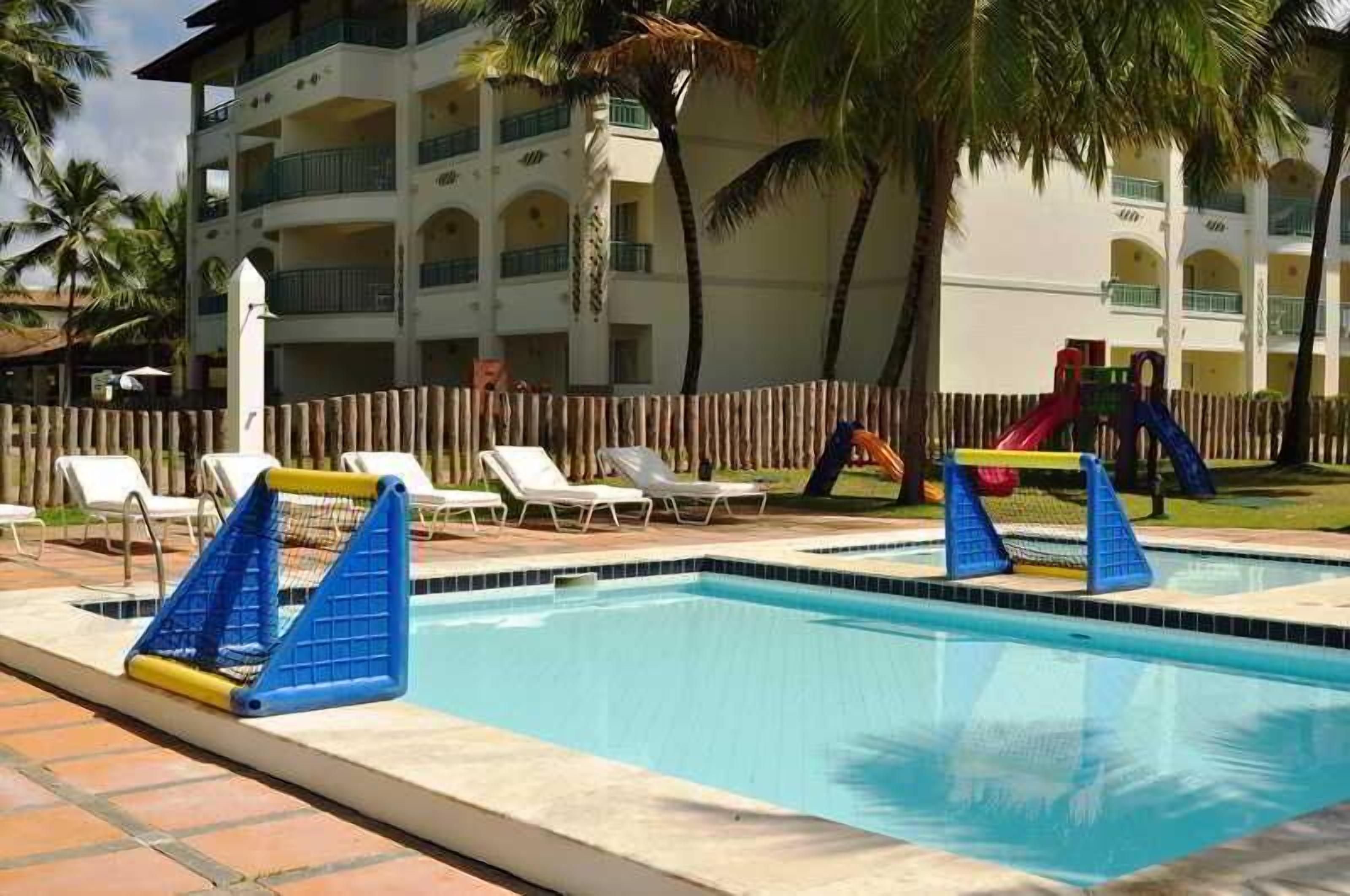 Piscina com espreguiçadeiras e parquinho.