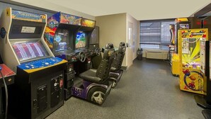 Uma fileira de máquinas de fliperama com jogos de corrida, uma máquina de garra e um distribuidor automático.