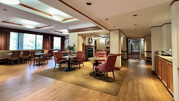 Um saguão de hotel com área de refeições, sofás e poltronas, e uma lareira.