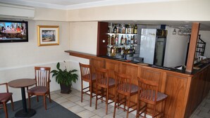 Uma área de bar com cadeiras de madeira e uma televisão fixada na parede.