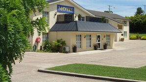 Um motel com placa, balcão de recepção e estacionamento.