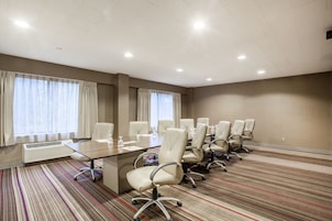 Uma sala de conferência com uma mesa comprida, várias cadeiras e piso coberto de carpete.