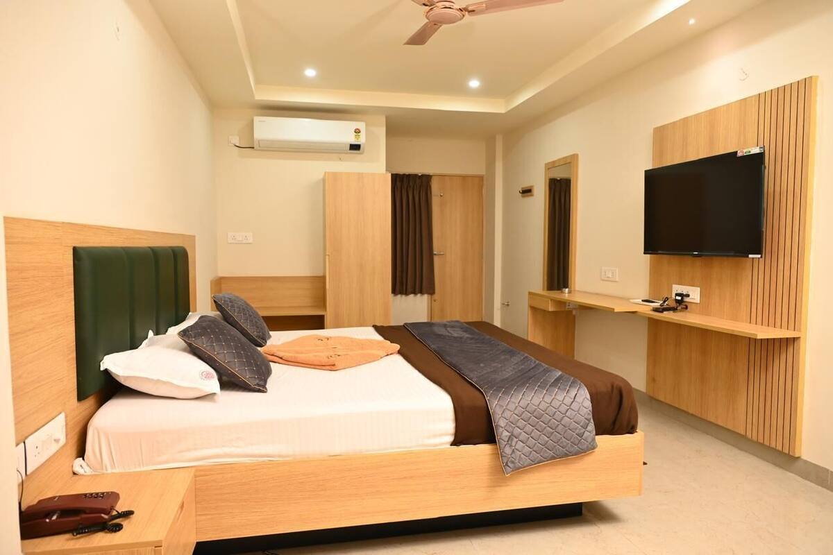 Quarto de hotel moderno com cama, televisão, guarda-roupa e ar condicionado.
