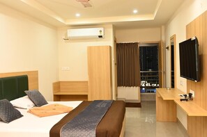 Quarto de hotel com cama, escrivaninha, televisão, ar condicionado e vista para o exterior.