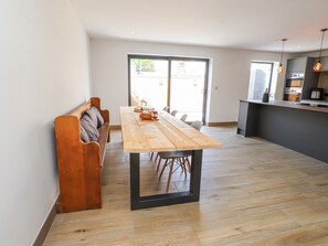 Uma cozinha moderna com mesa e banco de madeira, uma porta de vidro deslizante e uma pequena ilha com pia.