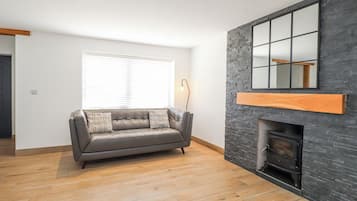 Uma sala de estar moderna com um sofá de couro, lareira e uma parede de destaque em pedra.