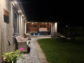Área de varanda externa com banheira de hidromassagem, assentos e churrasqueira.
