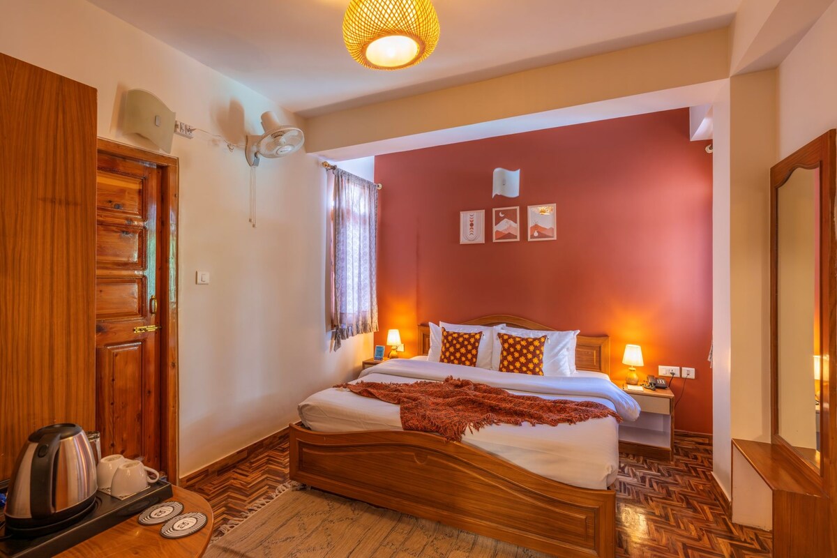 Quarto de hotel com cama de madeira, mesa de cabeceira com abajur, aquecedor e guarda-roupa de madeira.